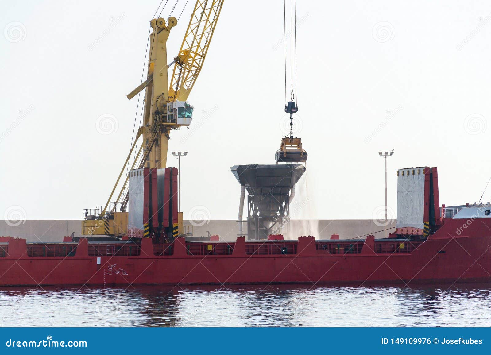 Yellow Crane Unloading Sand from Large Freighter Cargo Ship in Harbor ...