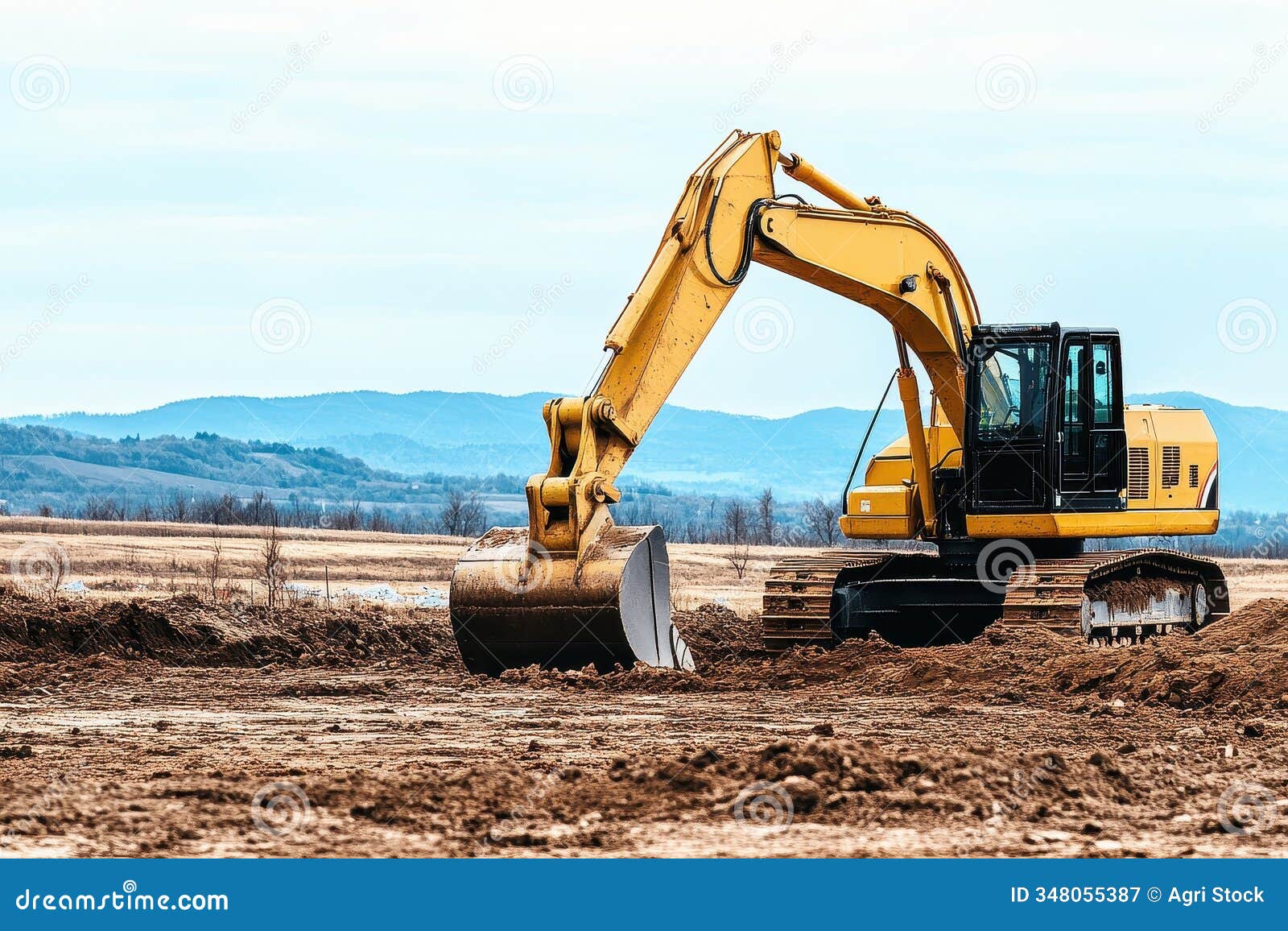 Yellow Excavator Digging in a Construction Site with Mountains in the ...