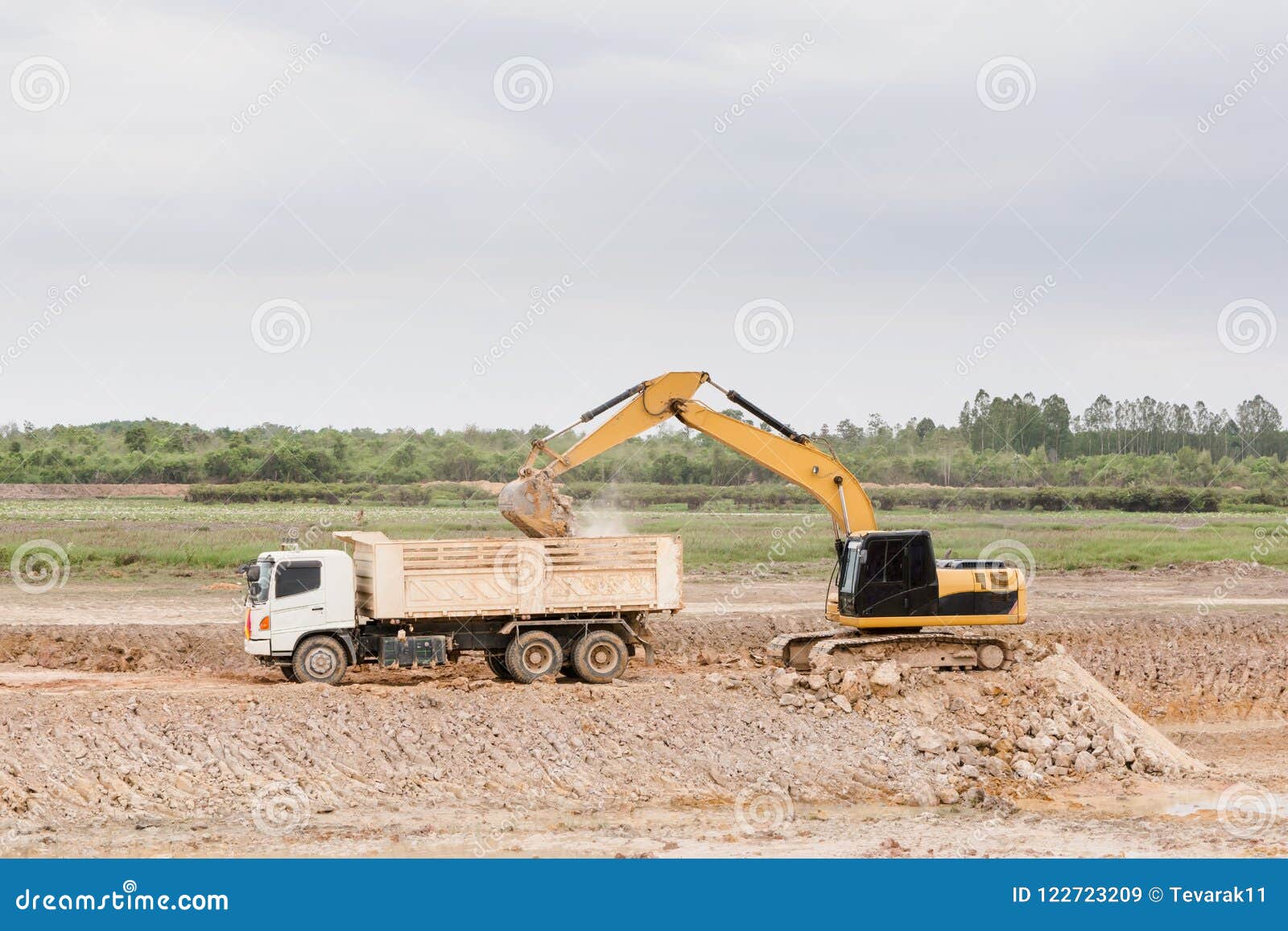 Yellow Excavator Machine Loading Soil into a Dump Truck at Construction ...