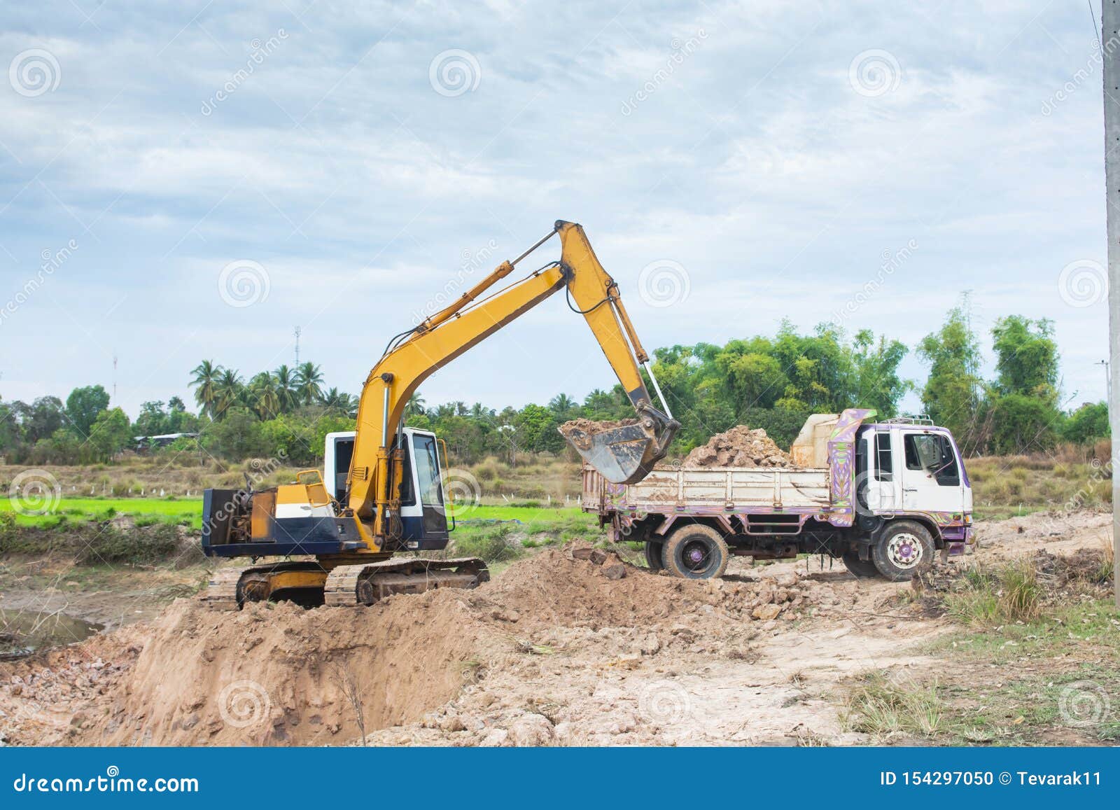 Yellow Excavator Machine Loading Soil into a Dump Truck at Construction ...