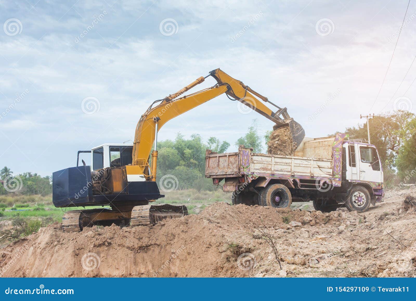 Yellow Excavator Machine Loading Soil into a Dump Truck at Construction ...