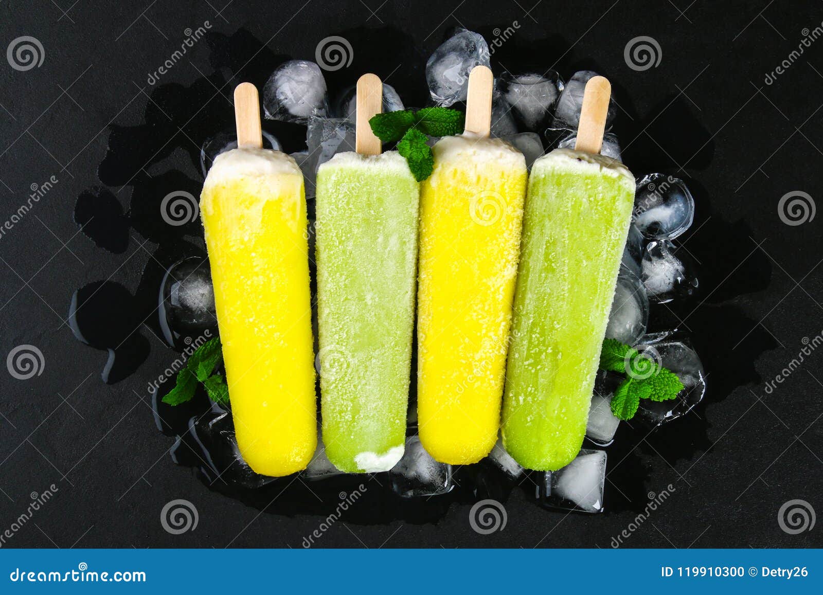 Yellow and Green Fruit Ice Cream on a Stick with Mint on Ice on a Black ...