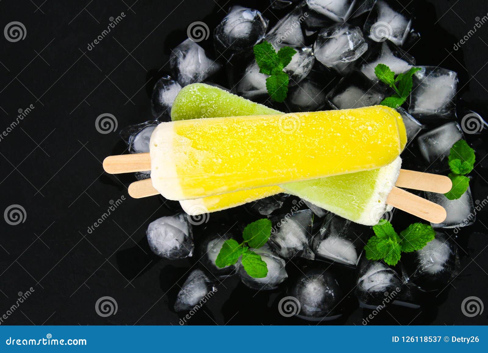 Yellow and Green Fruit Ice Cream on a Stick with Mint on Ice on a Black ...