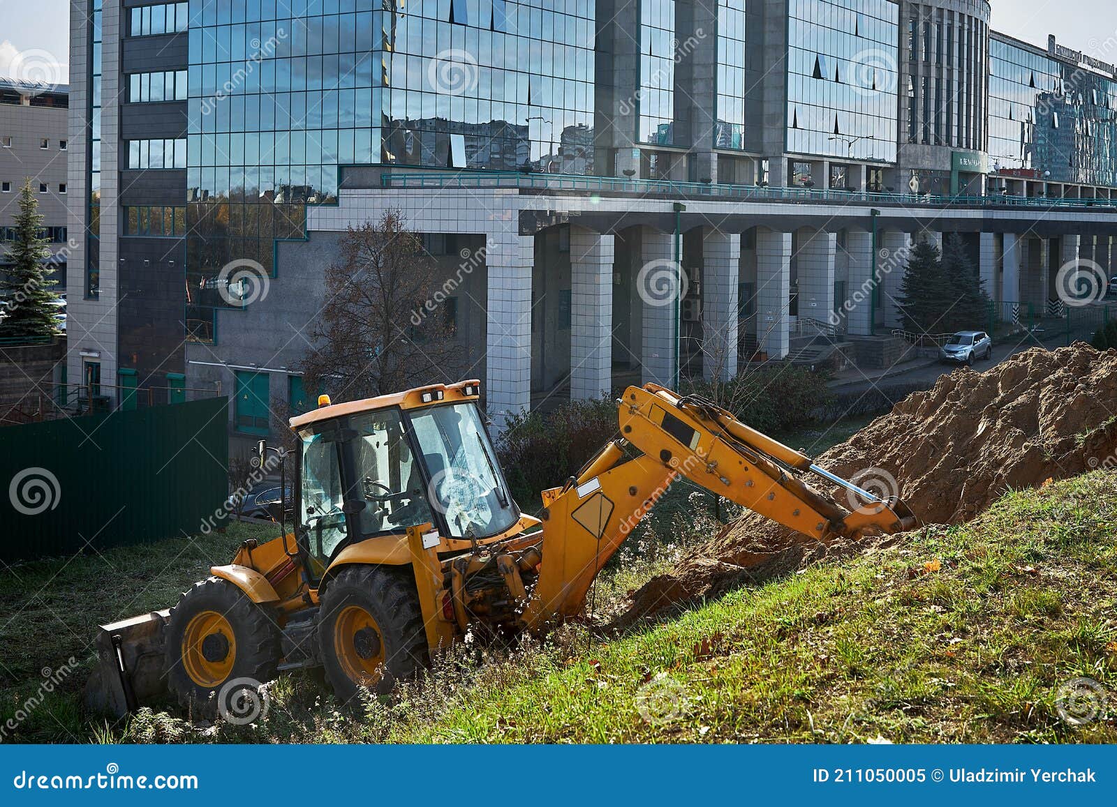 Yellow Loader Backhoe Digs Under the Road during Road Construction ...