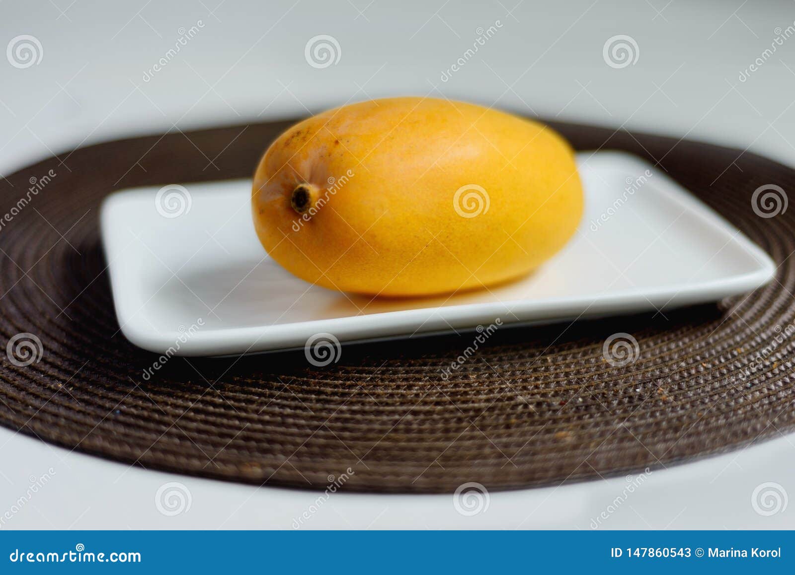 Yellow Mango is on the White Plate. Brown Tablecloth is Under the Plate ...