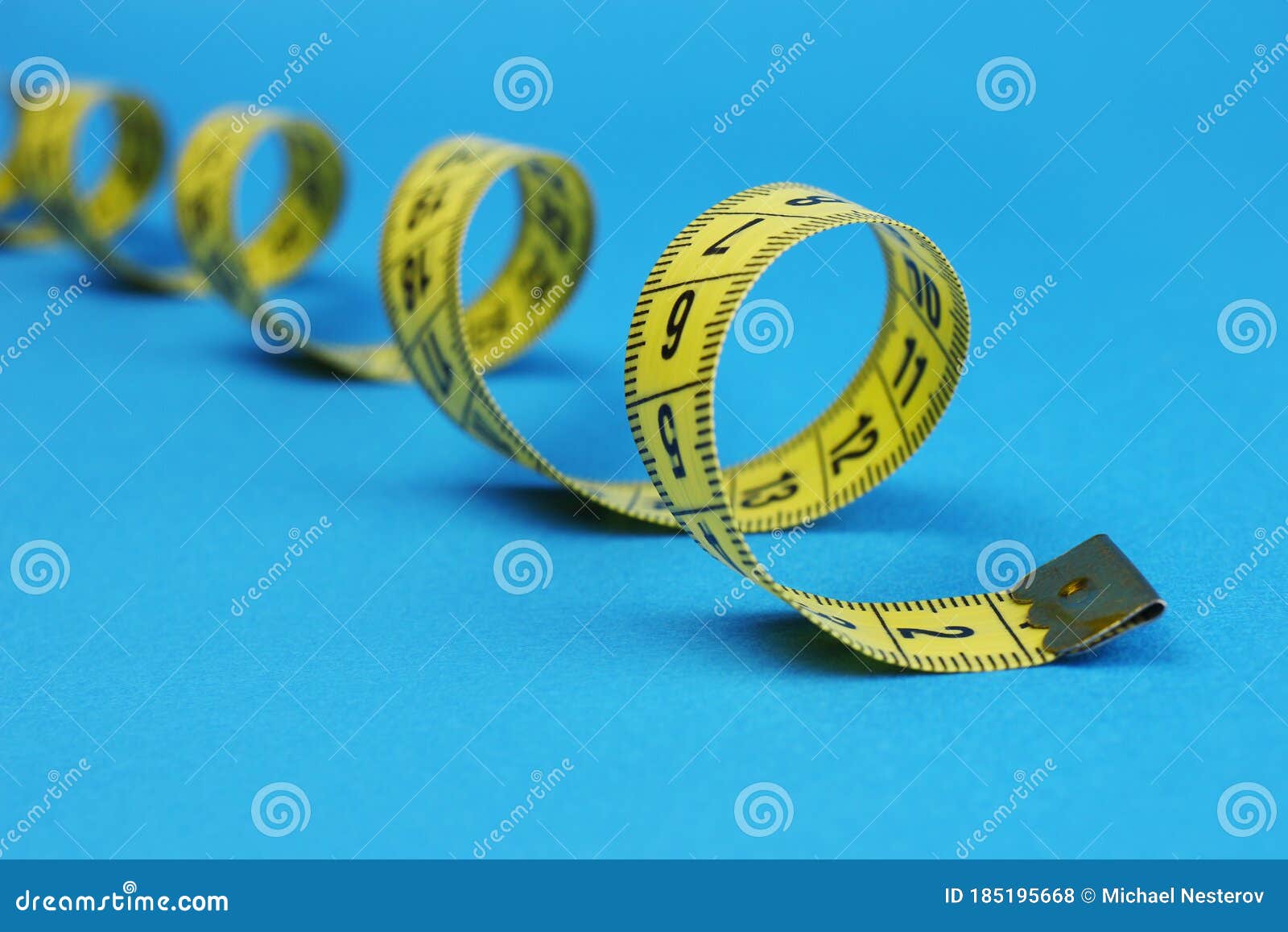 Yellow Measuring Tape is Twisted in a Spiral on a Blue Background Stock ...