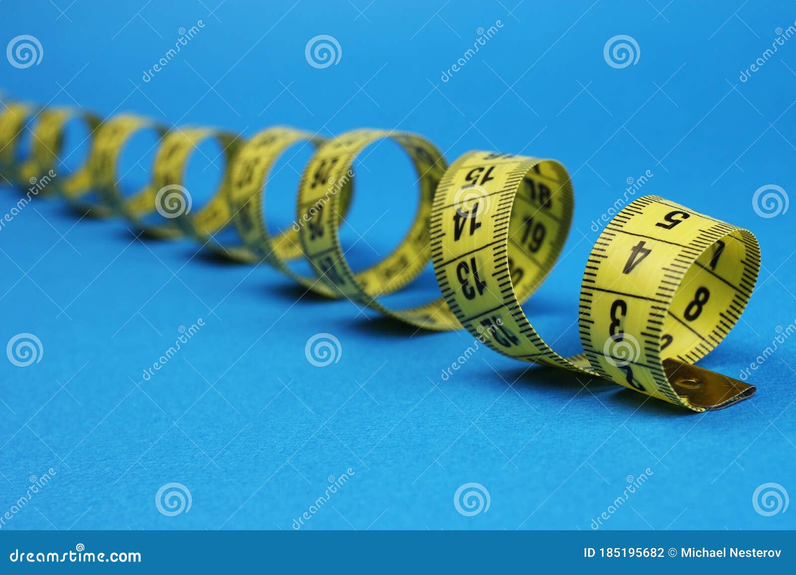Yellow Measuring Tape is Twisted in a Spiral on a Blue Background Stock ...