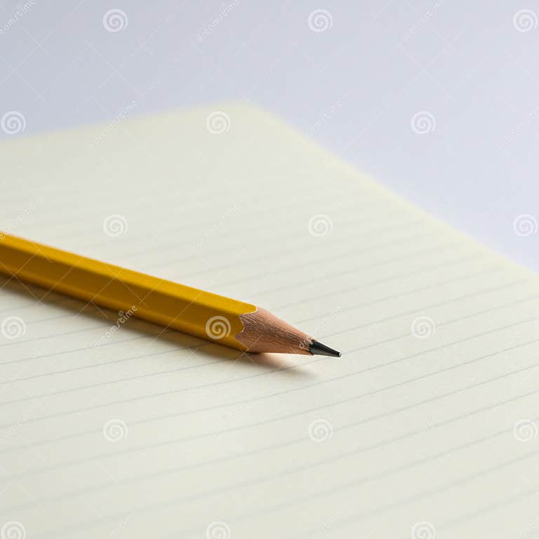 A Yellow Pencil with a Sharpened Tip Rests on a Blank, Lined Notebook ...