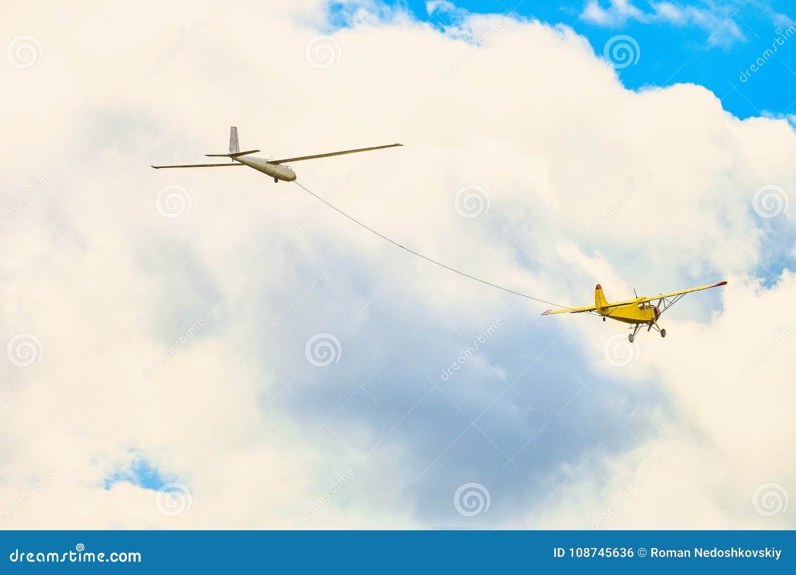 Yellow Small Light-engine Sport Plane Flying in the Cloudy Sky Pulls on ...