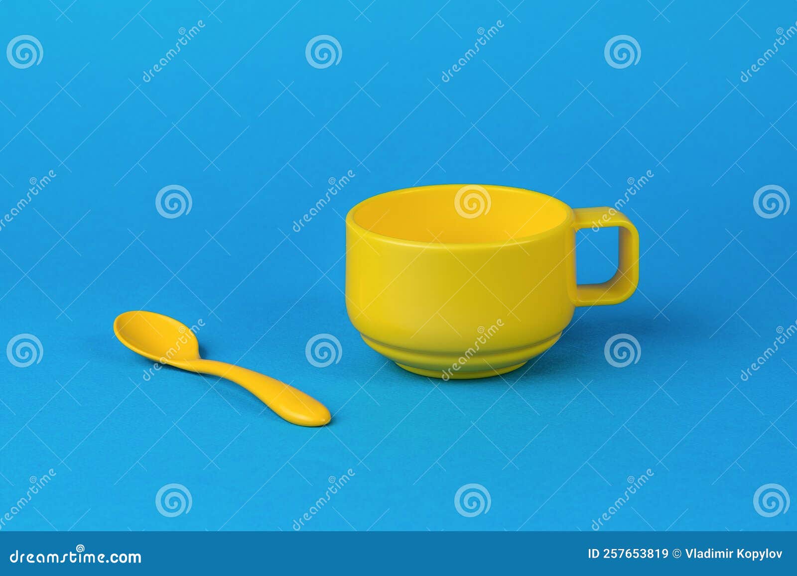 A Yellow Spoon Next To a Yellow Bowl with a Handle on a Blue Background ...