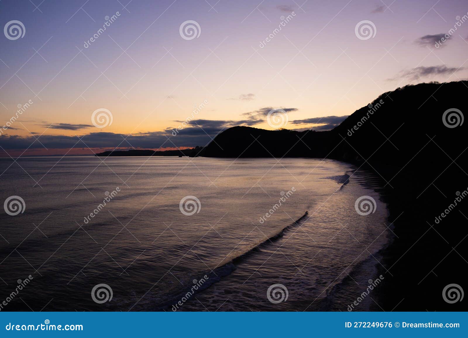 Yellow Sunset Behind the Cliffs with a Curving Beach Stock Photo ...