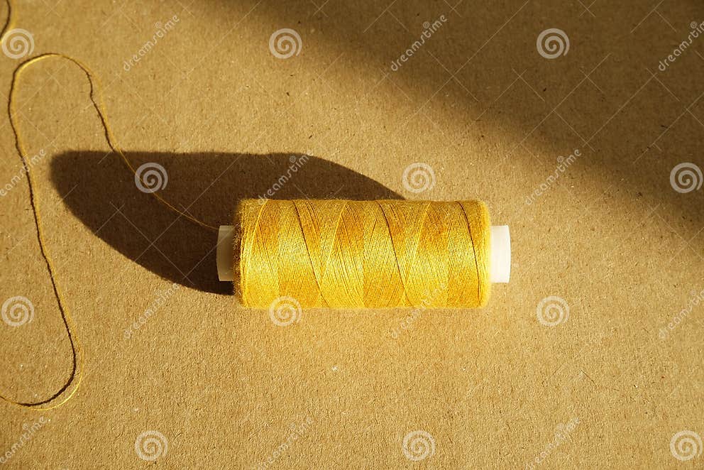 Yellow Thread Spool in Direct Sunlight on a Craft Background, Sewing ...