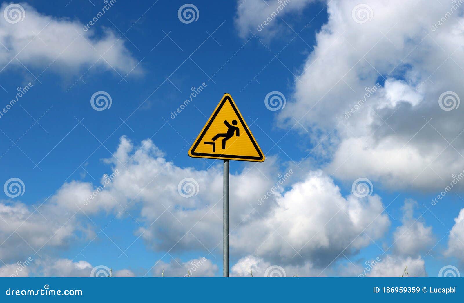 Yellow Triangular Falling Danger Sign Against Blue Sky with Fluffy ...