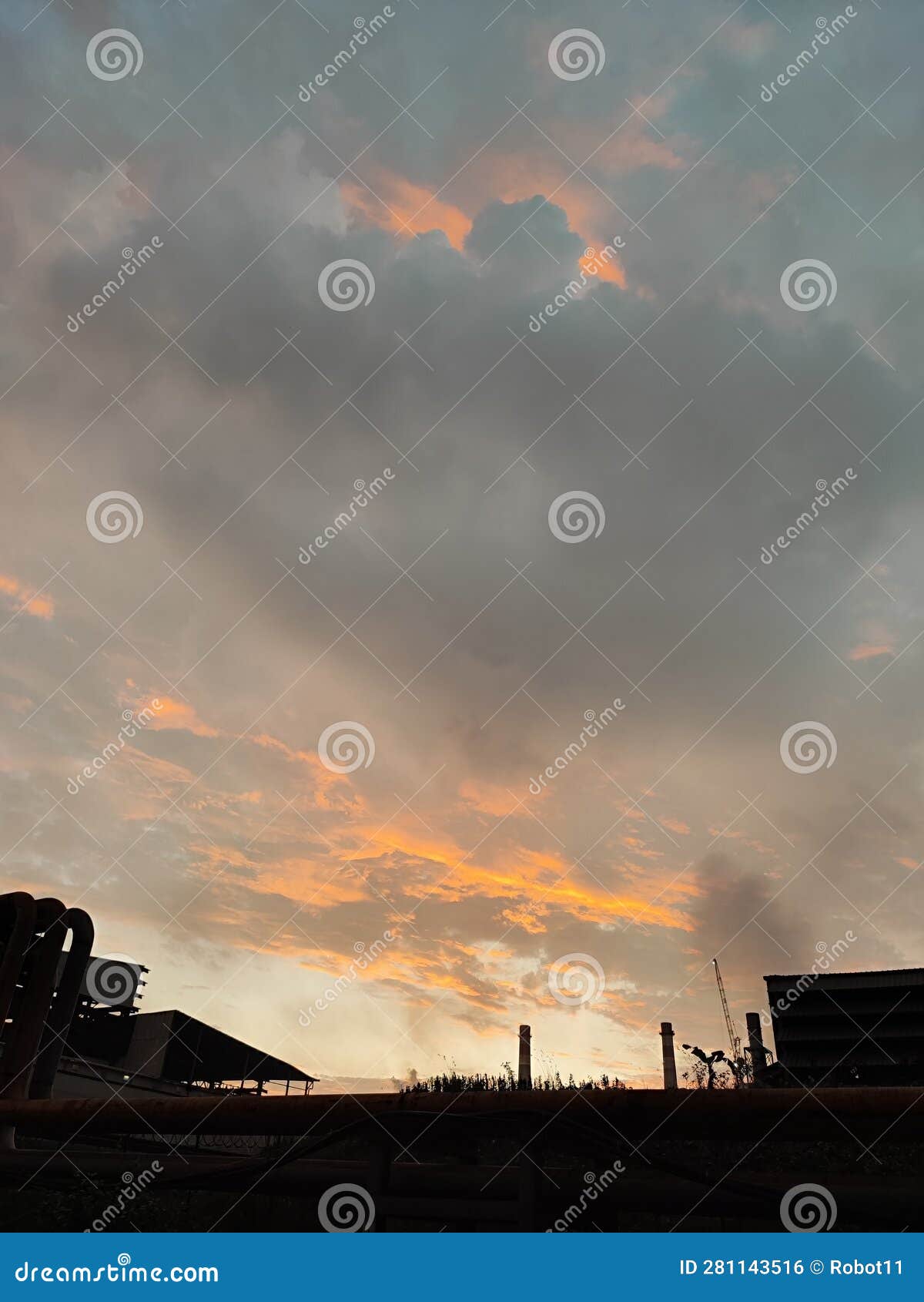Yellowish Evening Sky and White Clouds Over the Buildings and Pipes ...