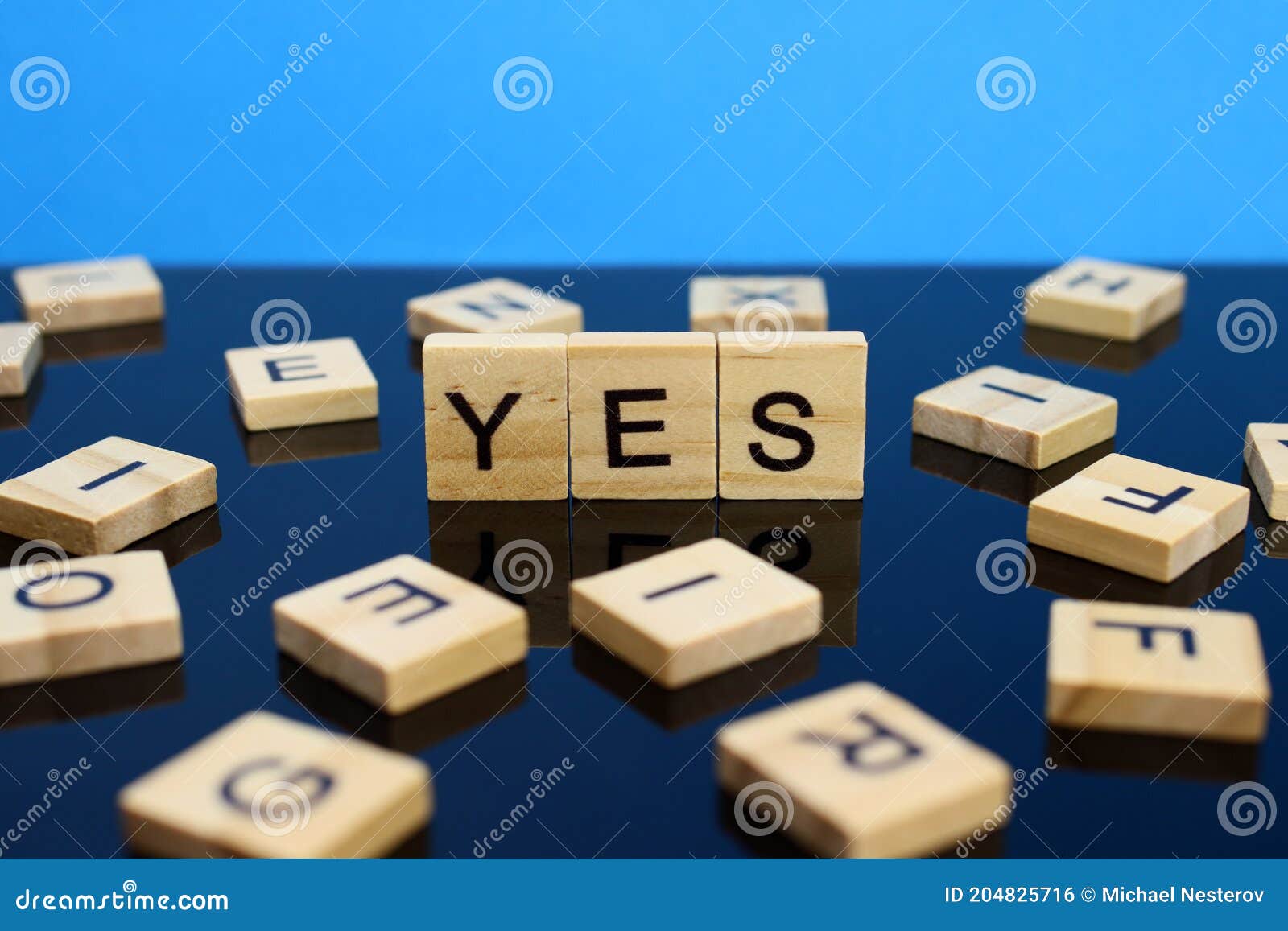 Yes Word Made of Wooden Letters on a Mirror Surface on a Blue ...