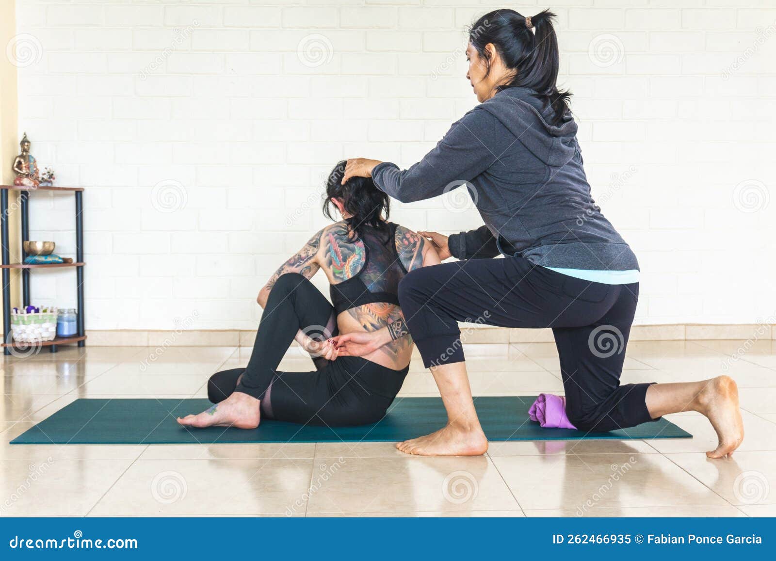 Yoga Instructor Correcting Posture of a Student Doing Ardha ...