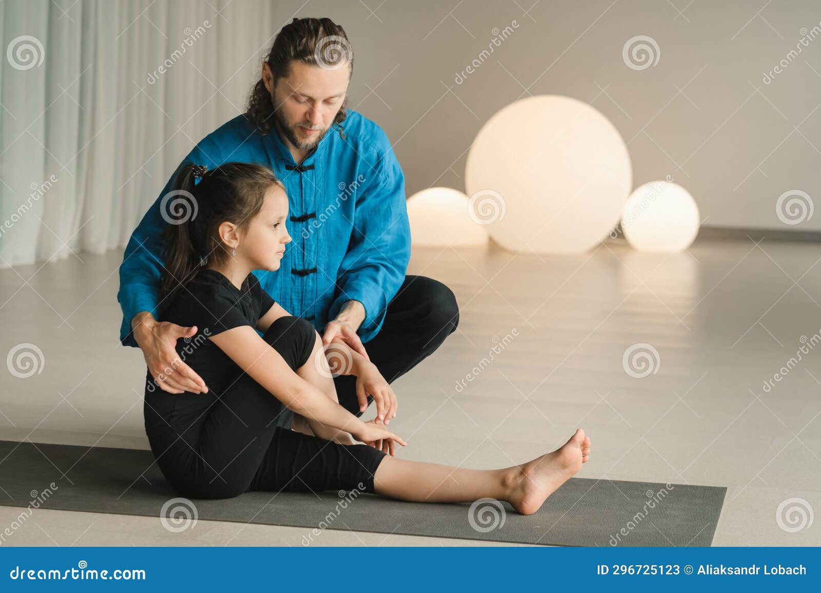 A Yoga Instructor in Training Helps a Child To Do Exercises in the Gym ...