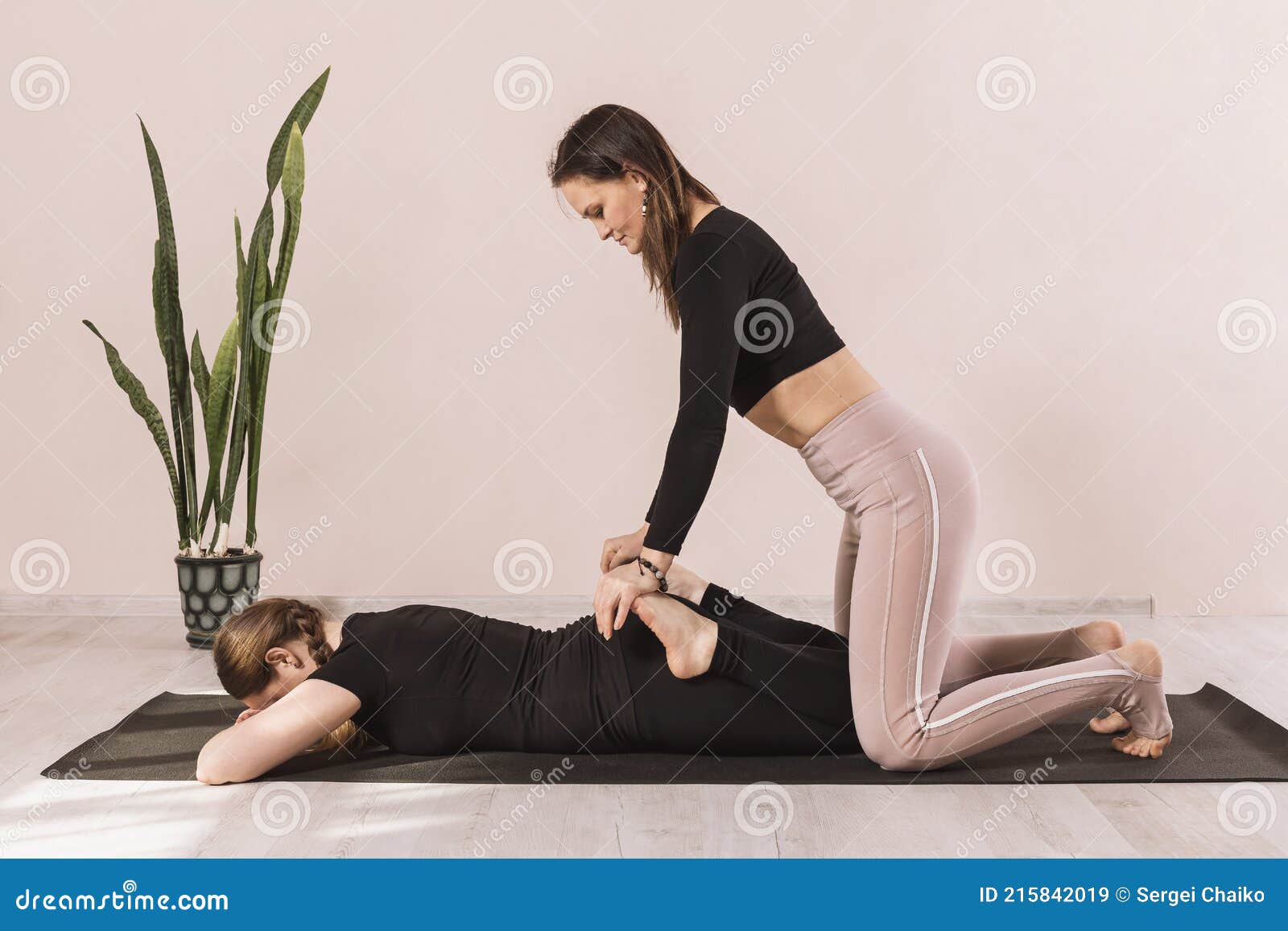 A Yoga Teacher Performs a Stretching Exercise for a Student in a Supta ...