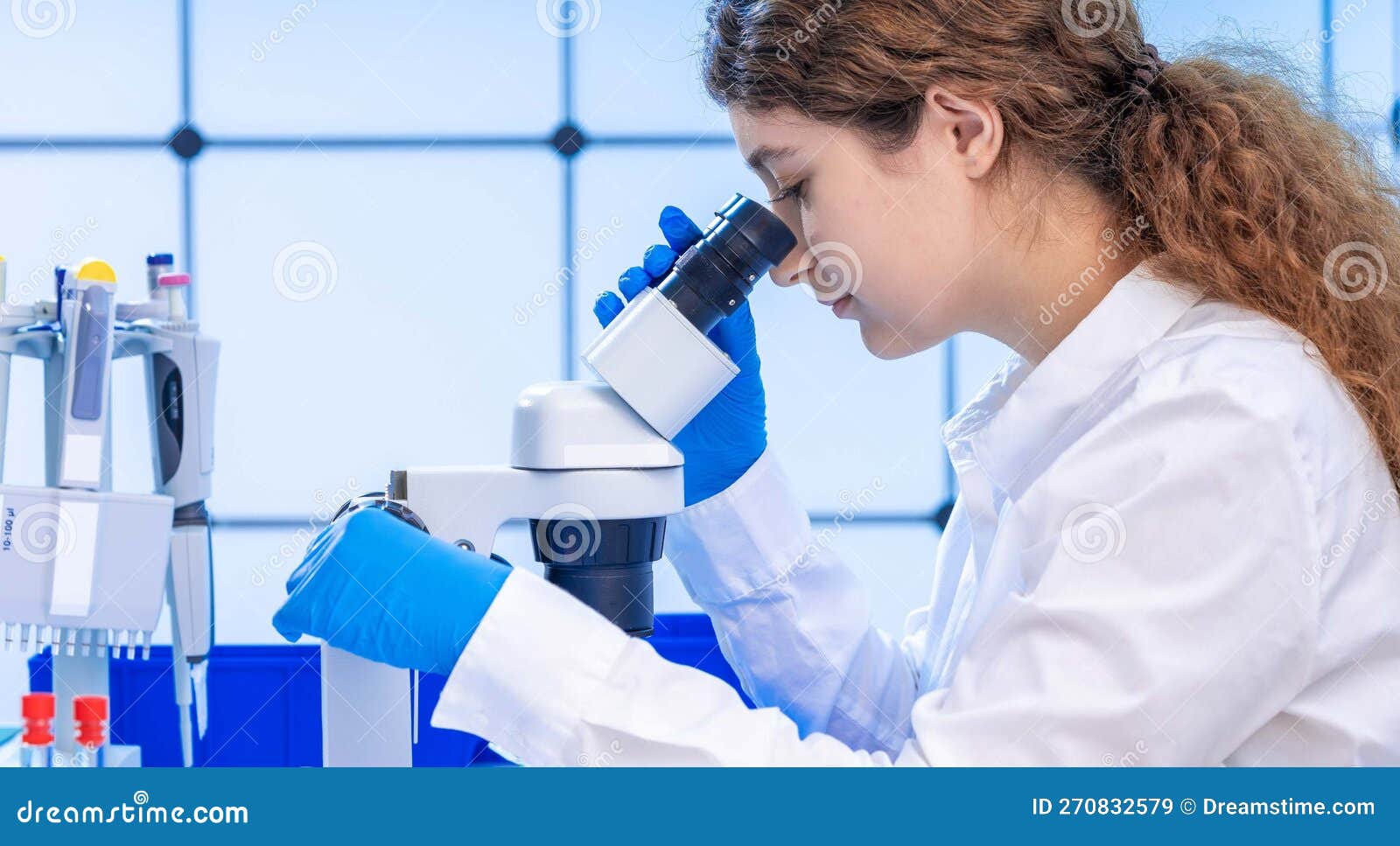 Young Adult Female Student Working with a Microscope Examining ...