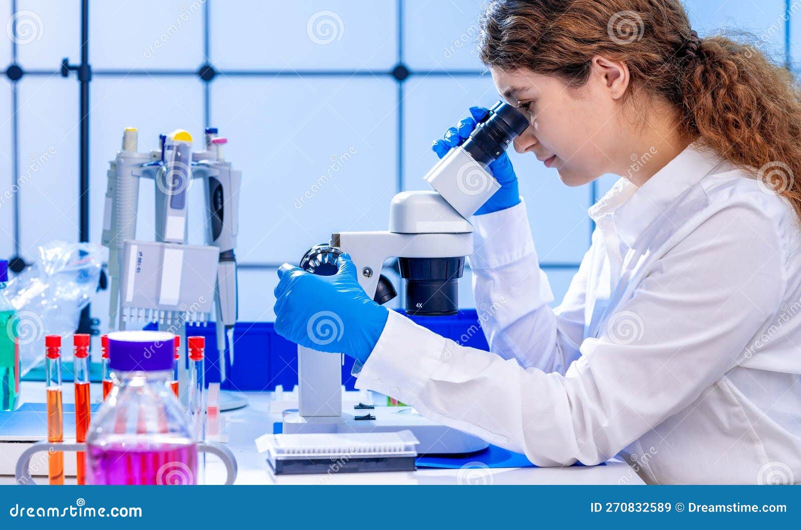 Young Adult Female Student Working with a Microscope Examining ...