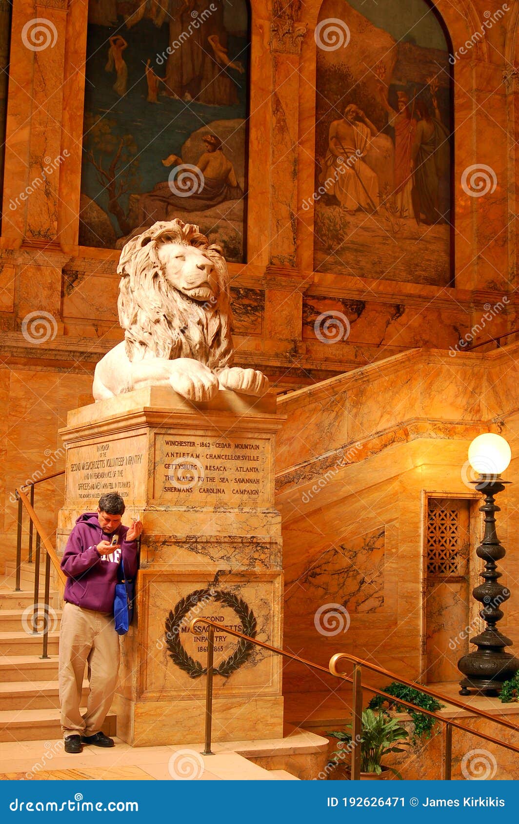 A Young Adult Texts while Standing Under a Statue of a Lion Editorial ...