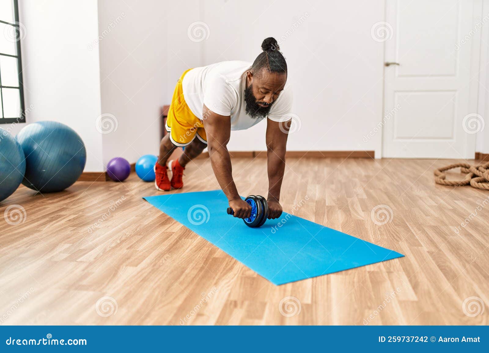 Young African American Man Training Abs Exercise Using Roller at Sport ...