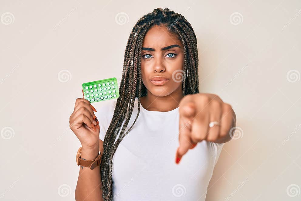 Young African American Woman With Braids Holding Birth Control Pills