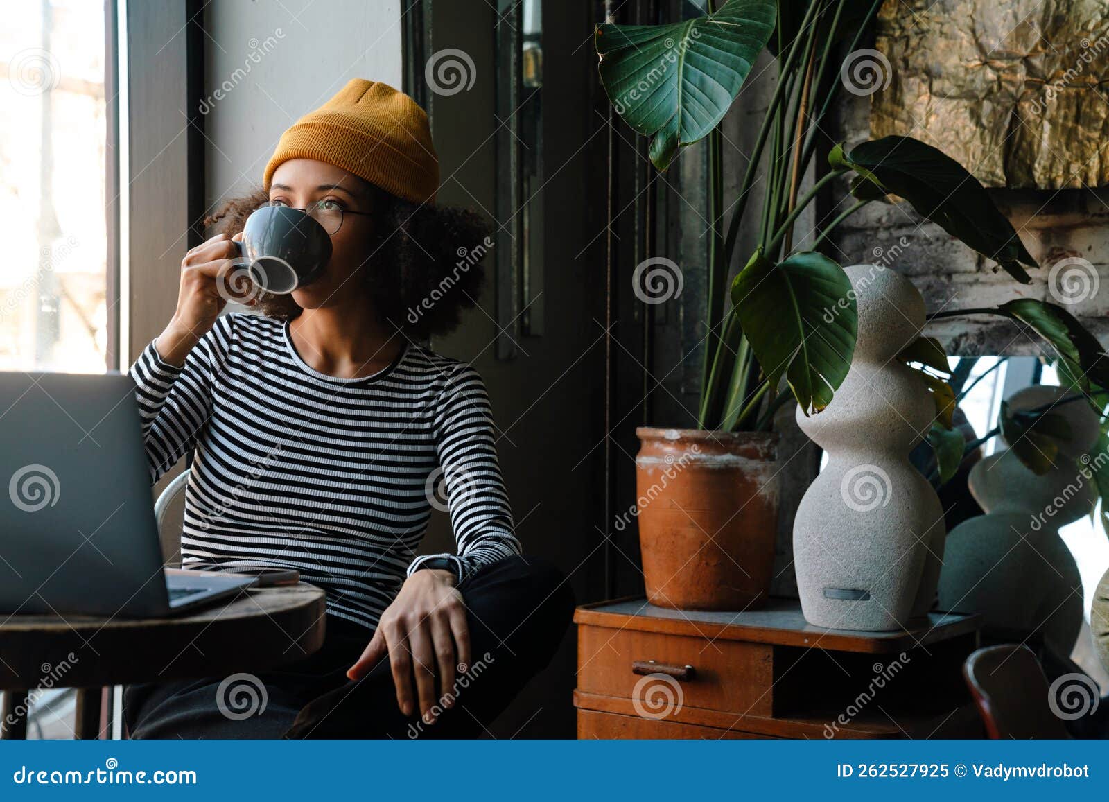 Young African American Woman Drinking Coffee While Sitting In Cafe