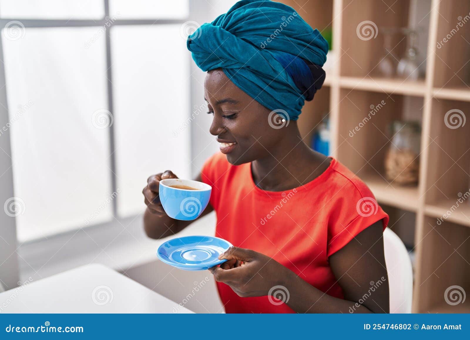 Young African American Woman Drinking Coffee Sitting On Table At Home