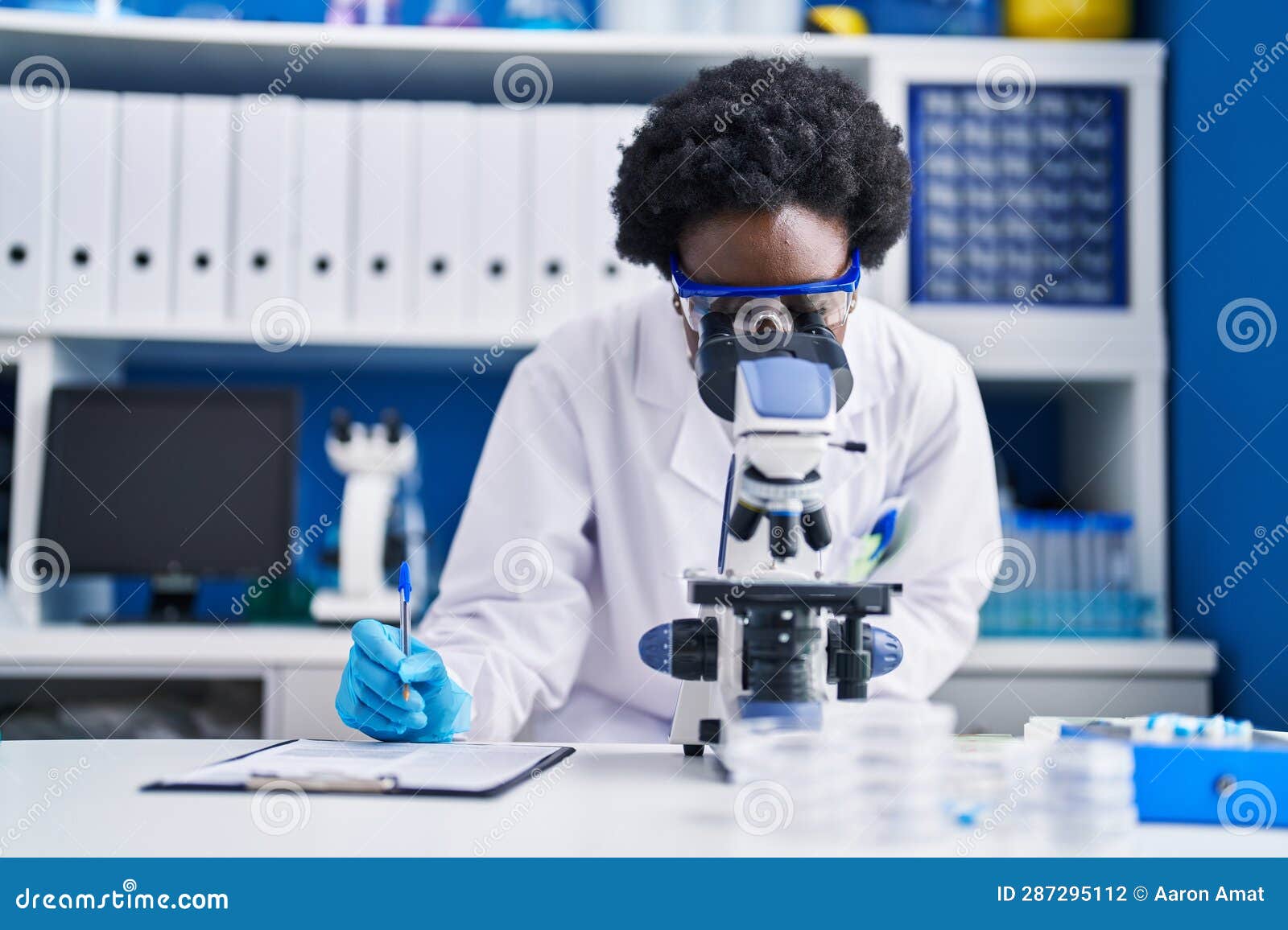 Young African American Woman Scientist Writing on Document Using ...