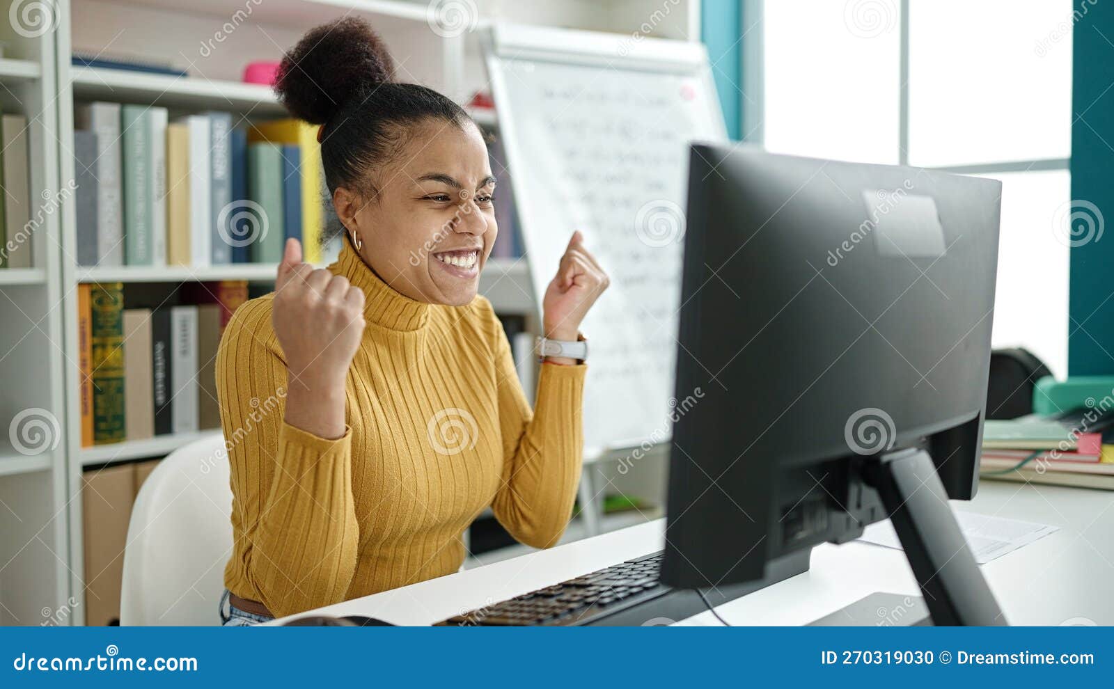 Young African American Woman Student Using Computer Celebrating at the ...