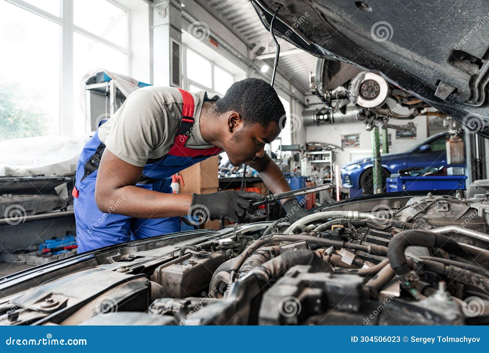 Young African Auto Mechanic Checking Car Engine Under the Hood in Auto ...
