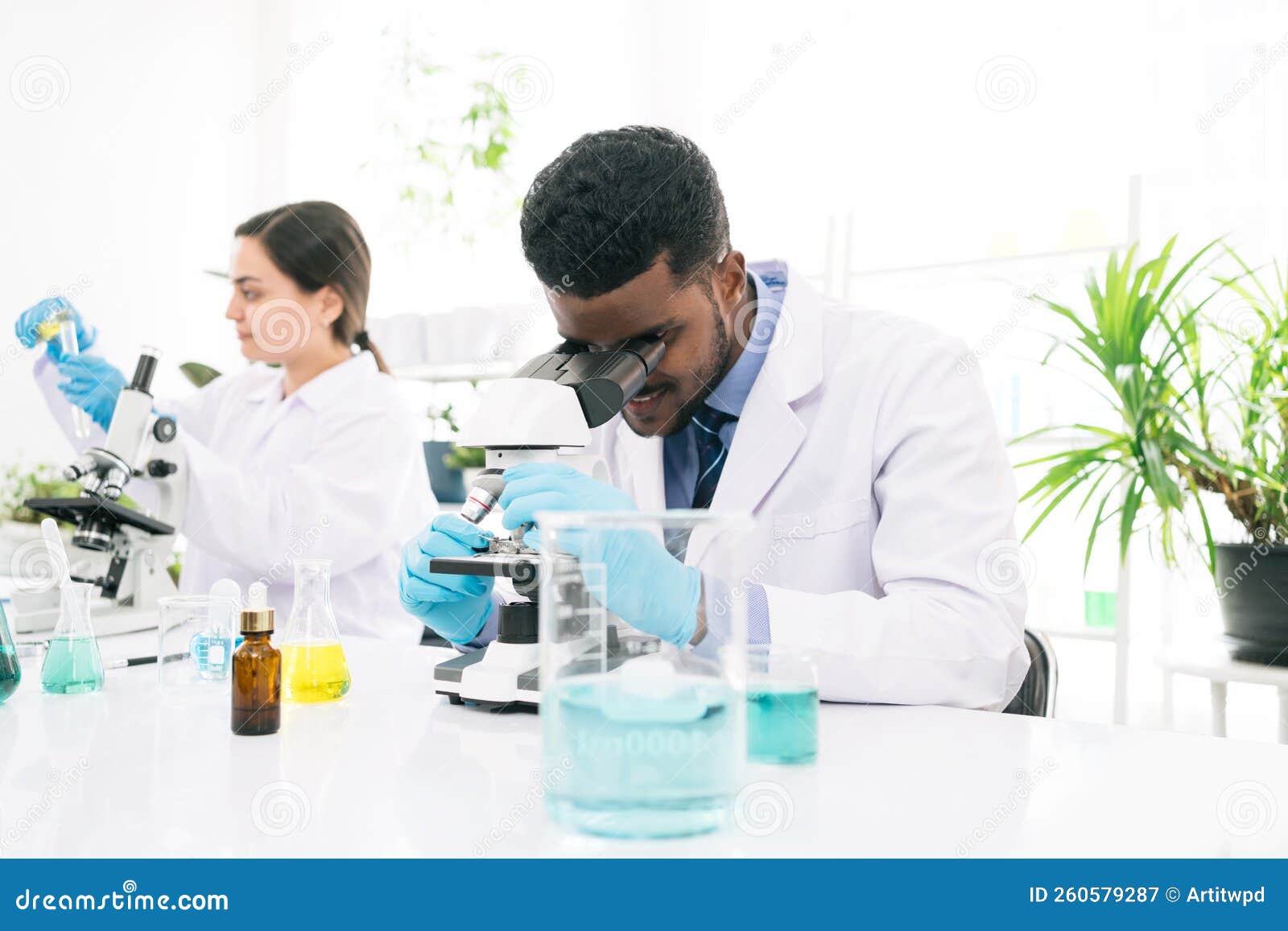 Young African Black Man Scientist Looking through a Microscope in a ...