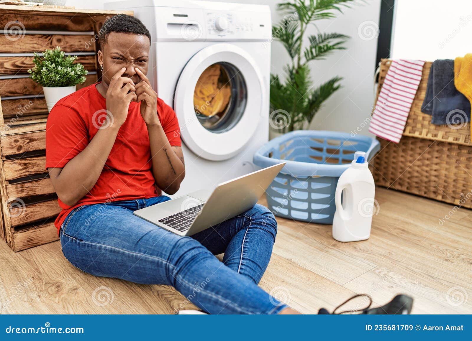 Young African Man Doing Laundry and Using Computer Smelling Something ...