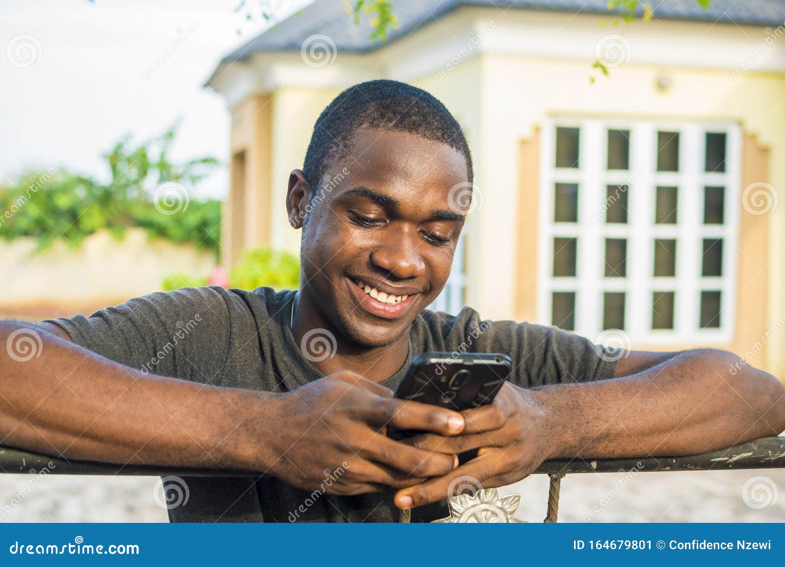 Young African Man Smiling and Using His Smartphone Stock Image - Image ...