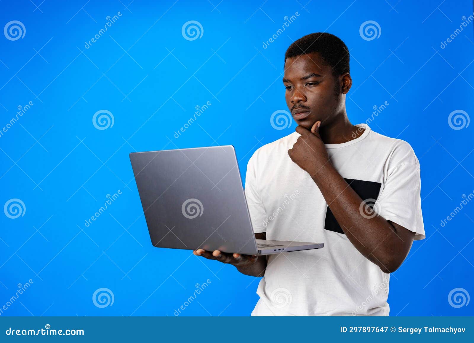 Young African Man Standing and Using Laptop Computer Over Blue ...