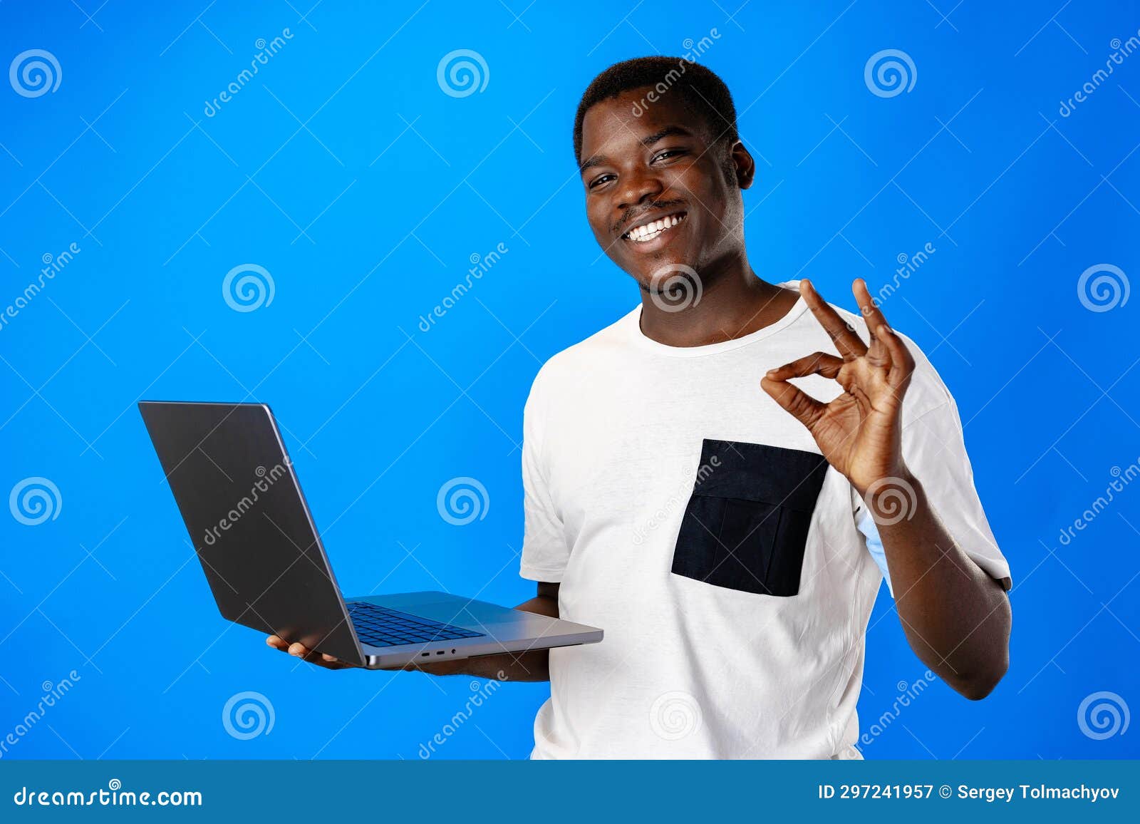 Young African Man Standing and Using Laptop Computer Over Blue ...