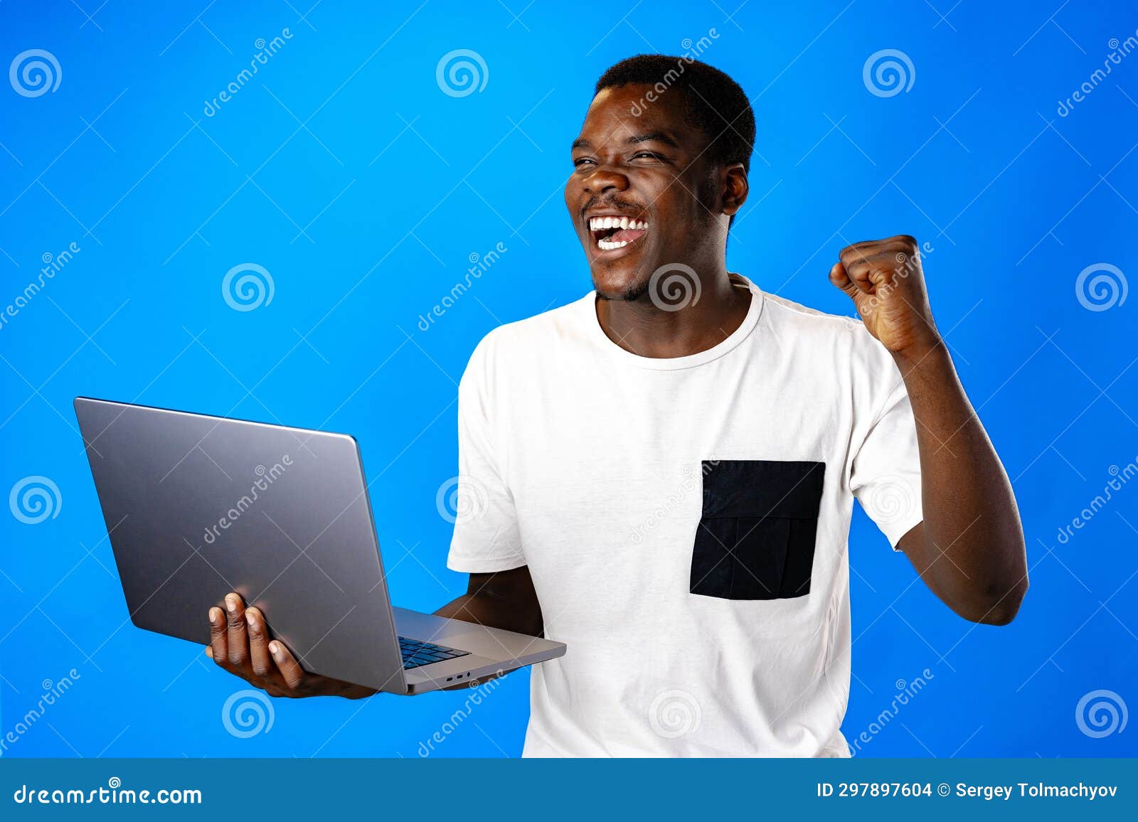 Young African Man Standing and Using Laptop Computer Over Blue ...