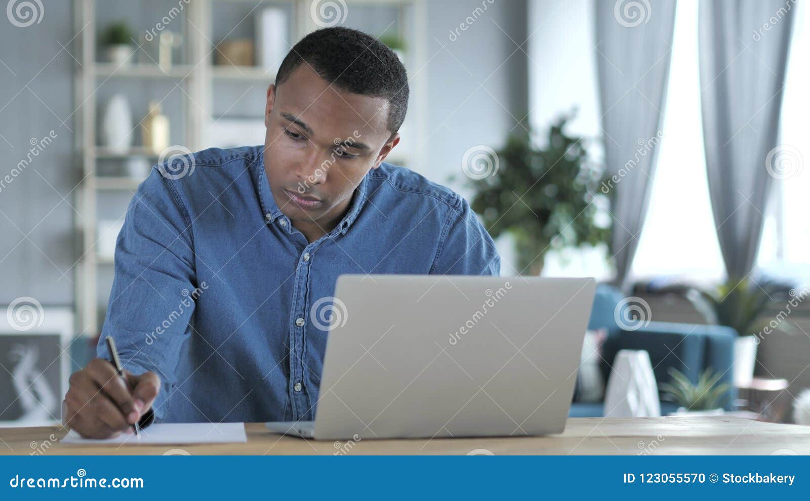 Young African Man Writing on Documents in Office Stock Photo - Image of ...