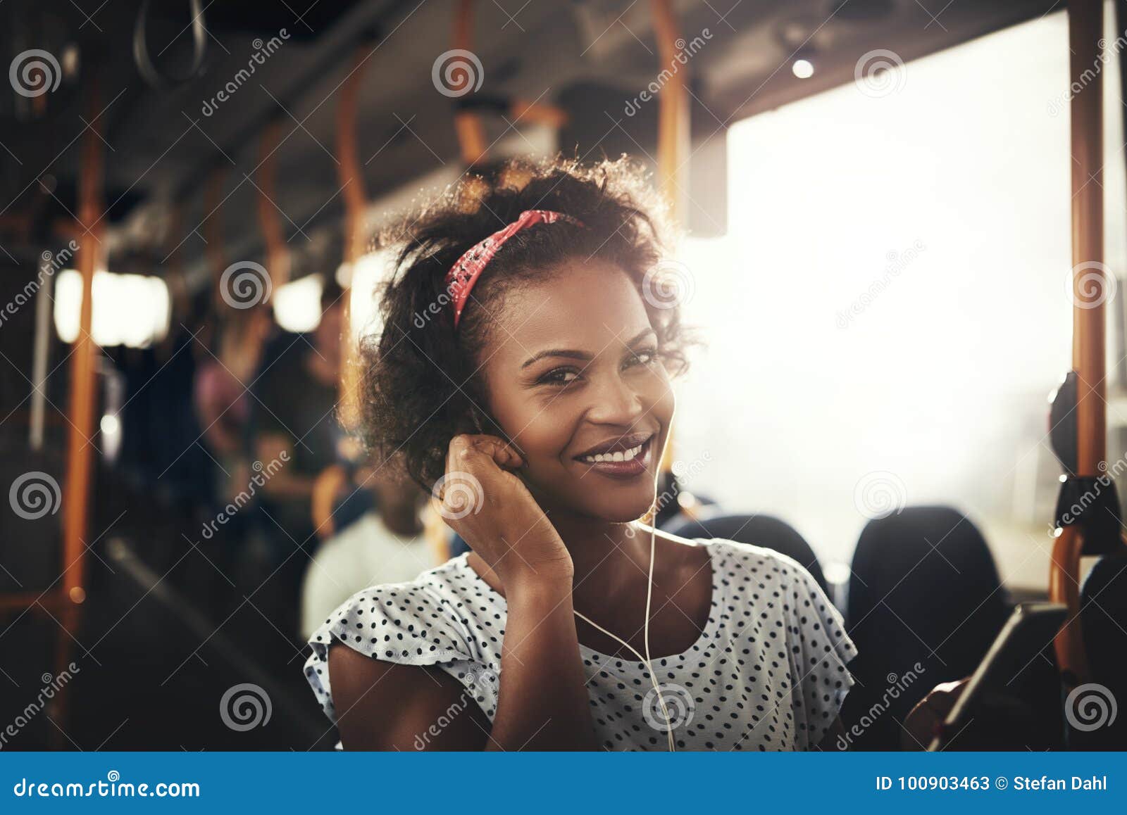 Smiling African Woman Standing On A Bus Listening To Music Stock Image