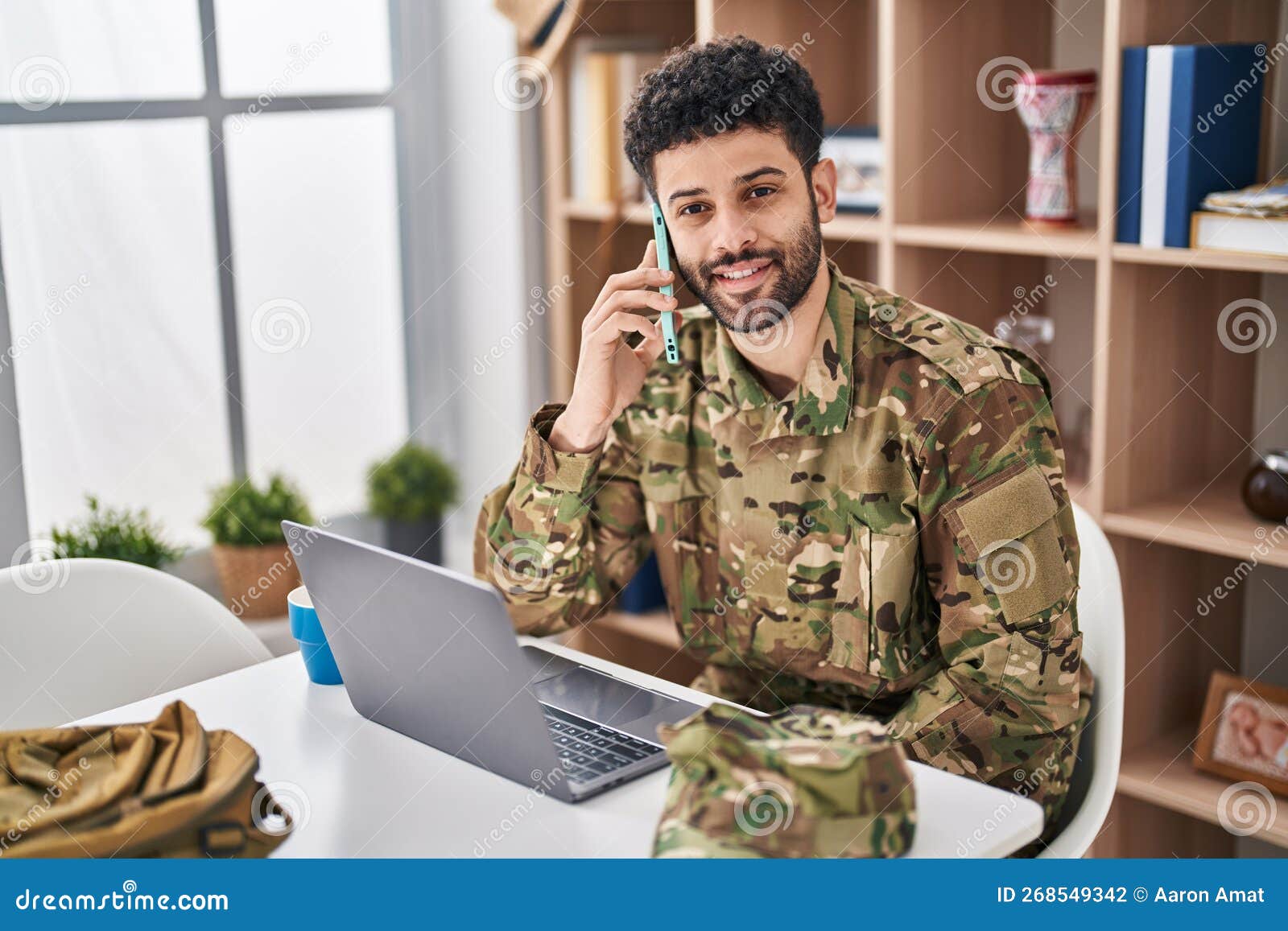Young Arab Man Army Soldier Using Laptop Talking on the Smartphone at ...