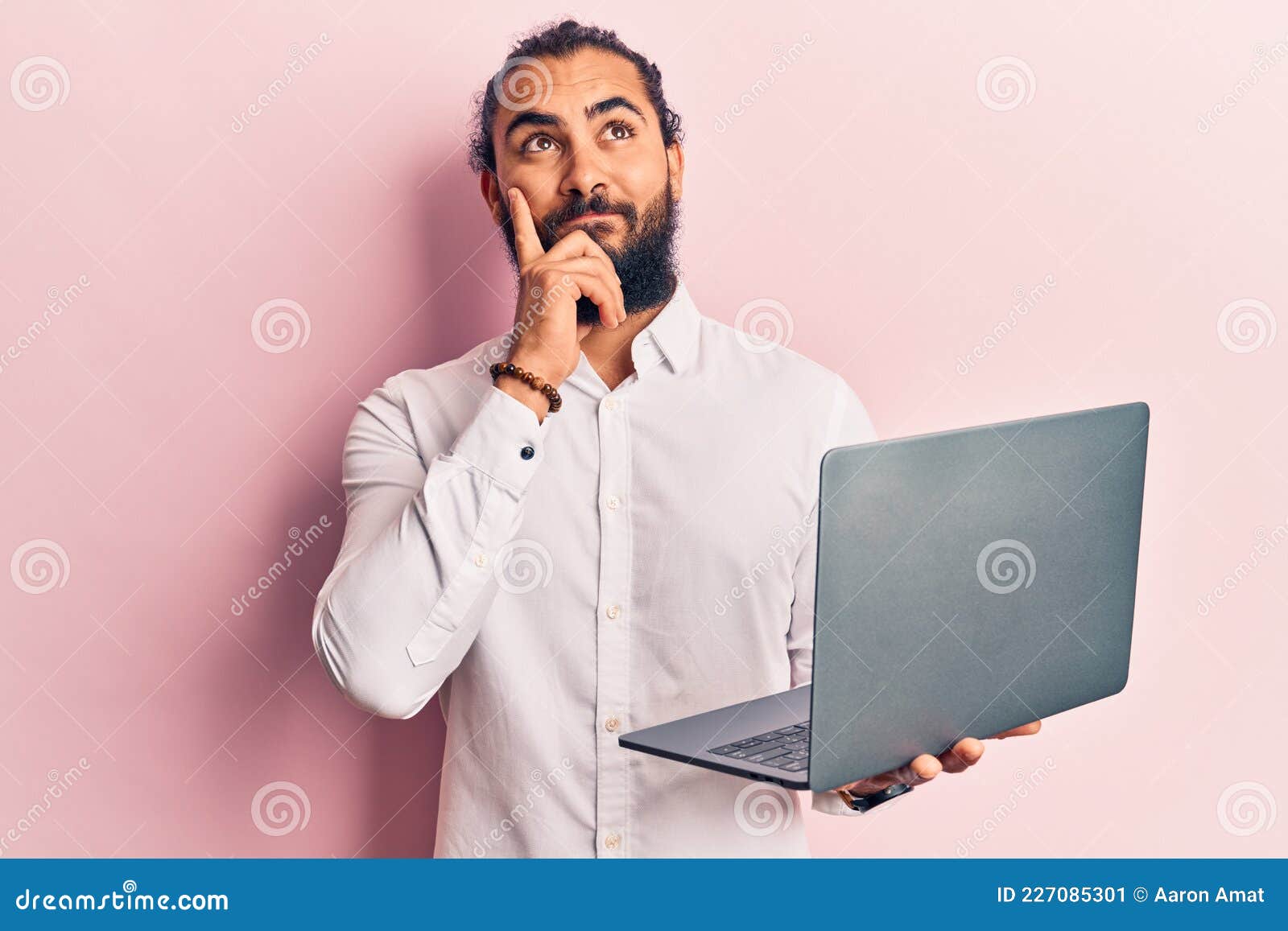Young Arab Man Holding Laptop Serious Face Thinking about Question with ...