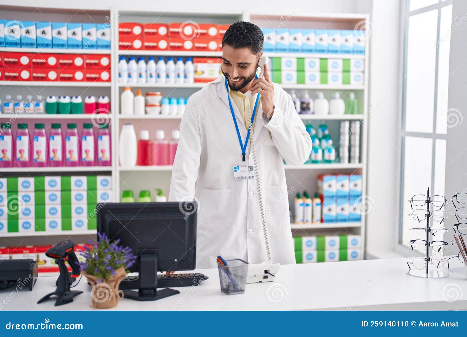 Young Arab Man Pharmacist Talking on Telephone Using Computer at ...