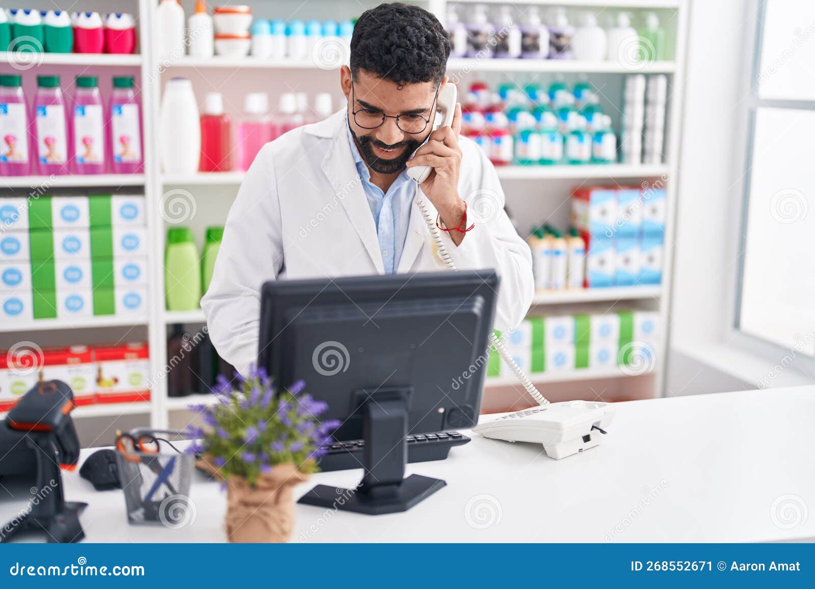 Young Arab Man Pharmacist Talking on Telephone Using Computer at ...