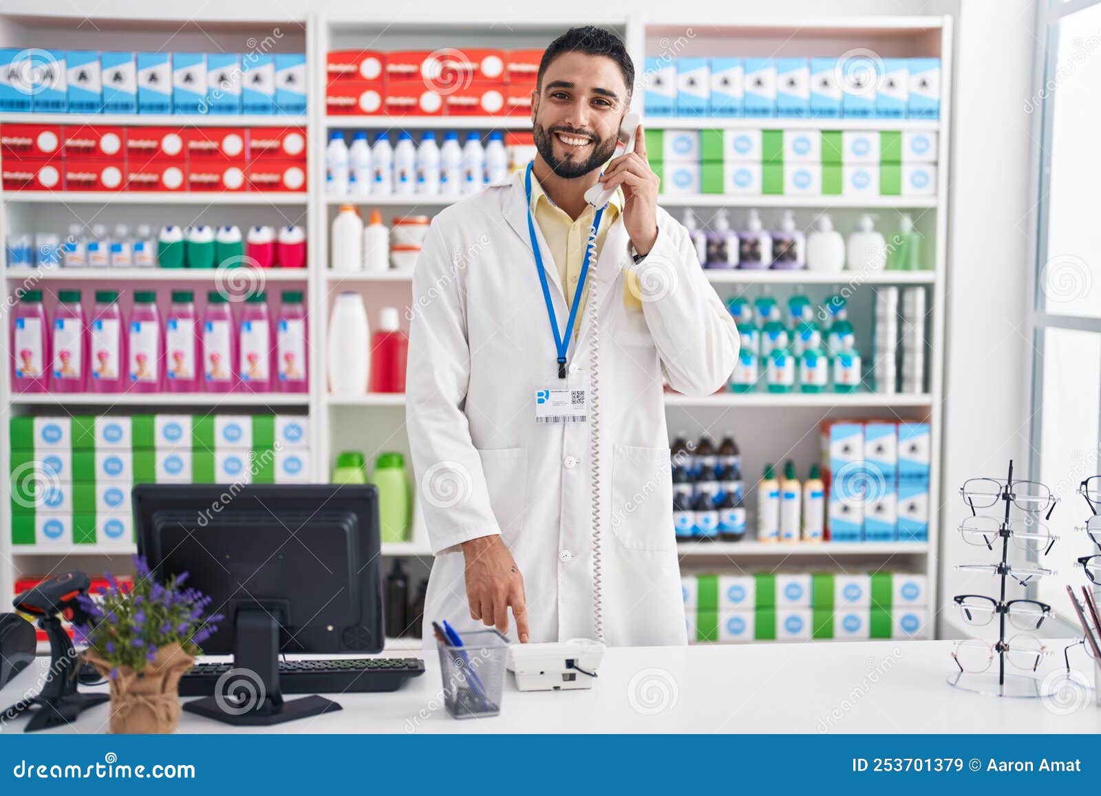 Young Arab Man Pharmacist Talking on Telephone Using Computer at ...