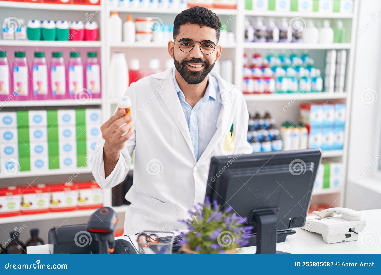 Young Arab Man Pharmacist Using Computer Holding Pills Bottle at ...