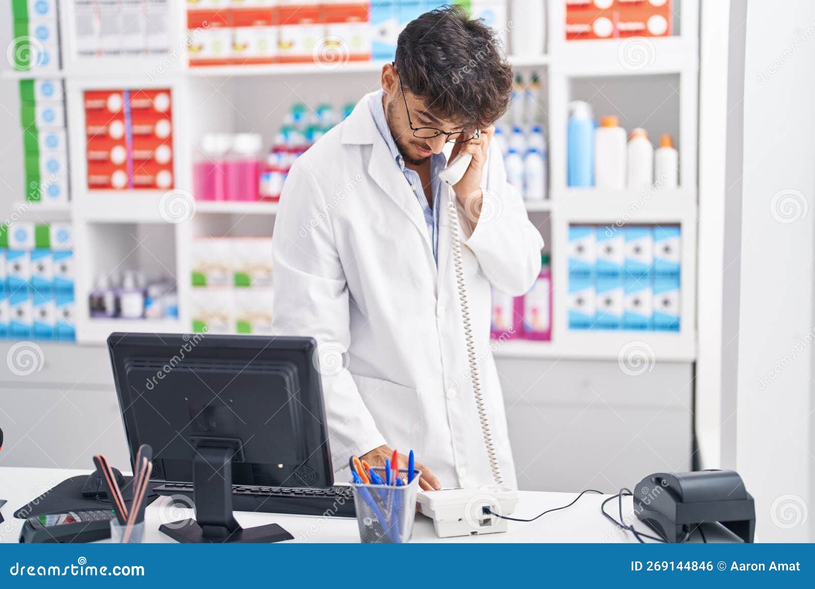 Young Arab Man Pharmacist Using Computer Talking on Telephone at ...