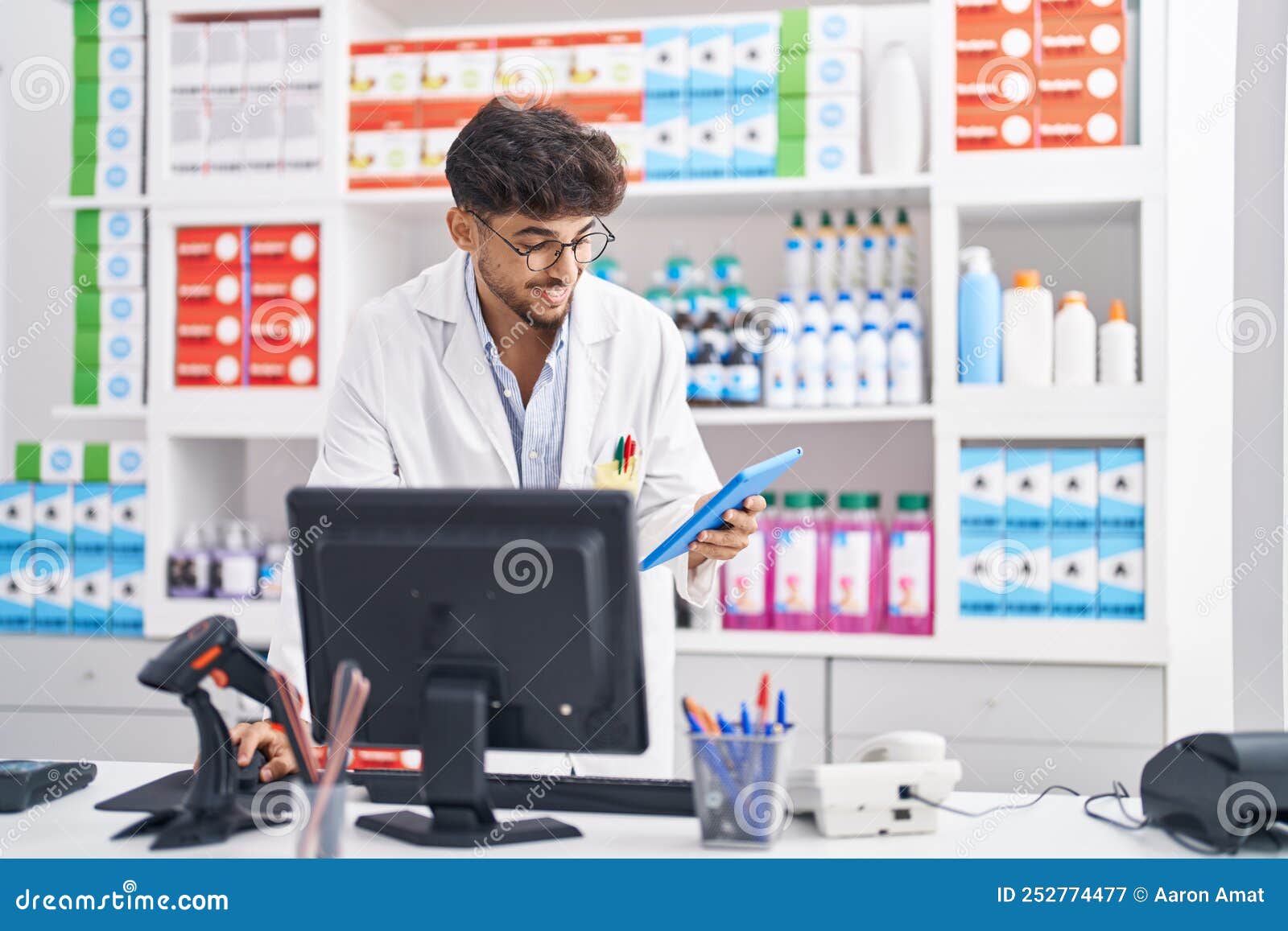 Young Arab Man Pharmacist Using Computer and Touchpad at Pharmacy Stock ...