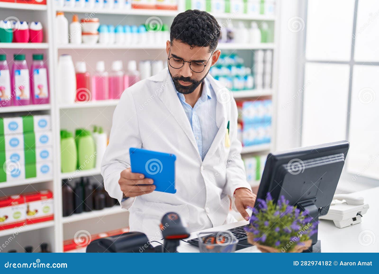 Young Arab Man Pharmacist Using Touchpad and Computer at Pharmacy Stock ...