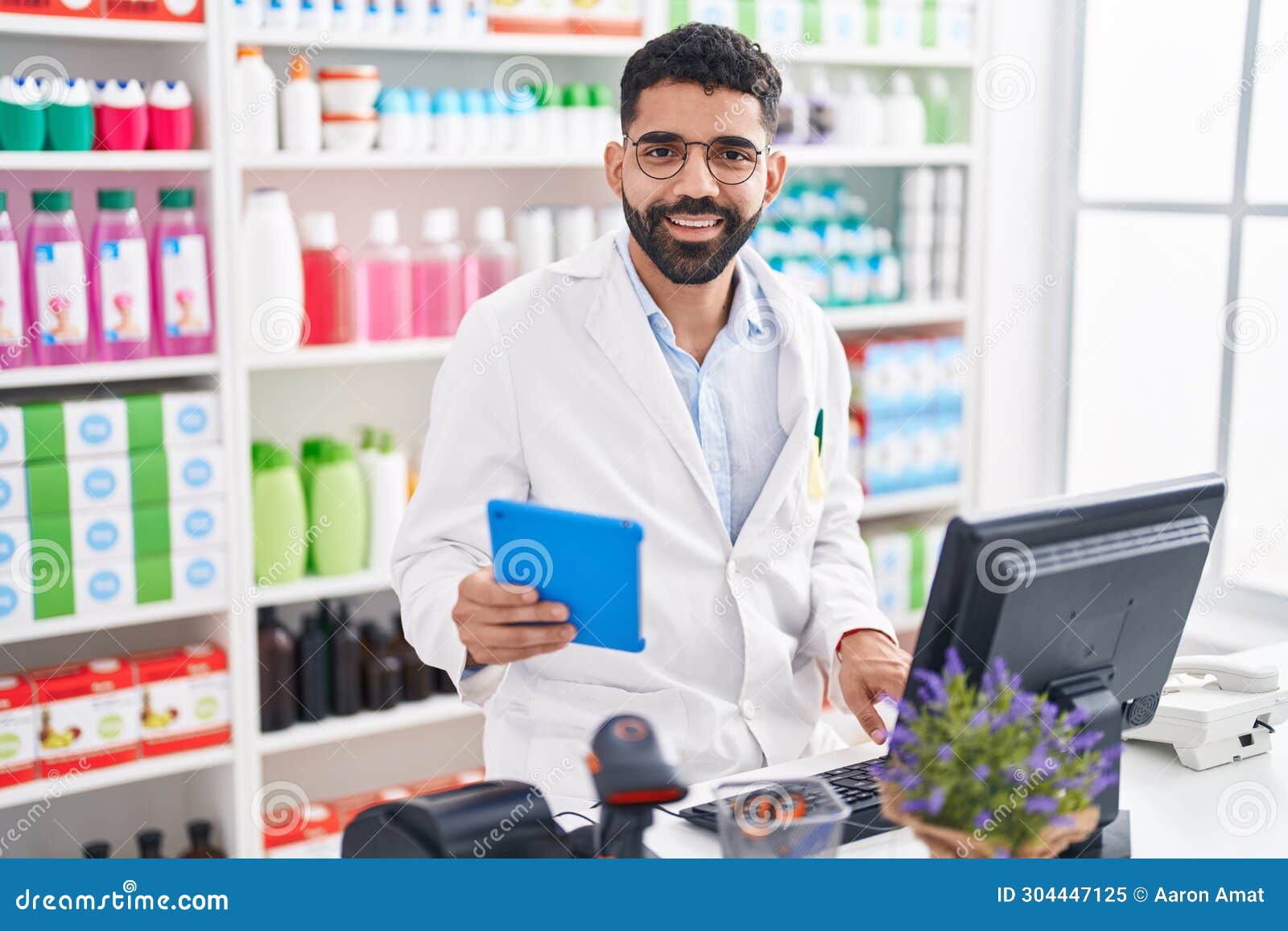 Young Arab Man Pharmacist Using Touchpad and Computer at Pharmacy Stock ...